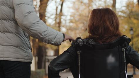 Disabled Woman Rolling In A Wheelchair On The Path In The Autumn Park