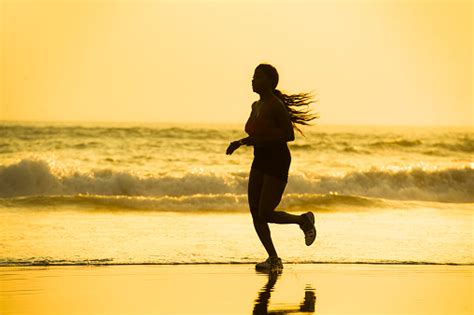 조깅 하 고 보건 의료 및 야외 활동에서 석양을 즐기는 아름 다운 해변에서 실행 피트 니스 운동에 운동 행복 하 고 매력적인 젊은 아프리카계 미국인 선수 여자의 실루엣