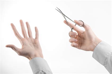 외과 및 의료 테마 스튜디오에서 흰색 배경에 고립 된 외과 클램프가 위를 들고 백색 실험실 외 투에 의사의 손을 강철에 대한