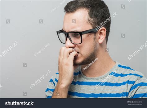 Closeup Portrait Of A Nerdy Young Guy With Glasses Biting His Nails