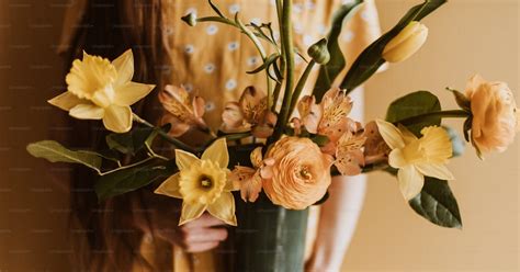 노란 꽃으로 가득 찬 꽃병을 들고 있는 여자 사진 Unsplash의 꽃의 이미지