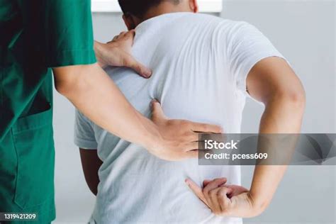 남자의 등에 치유 치료를하고 남성 의사 치료사 허리 통증 환자 치료 의사 허리 통증 완화 사무실 증후군 마사지 요법에 대한 스톡