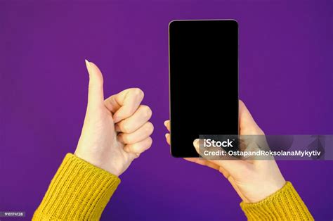 여자는 Oled 디스플레이 울트라 바이올렛 색상 년 배경으로 스마트 휴대 전화를 들고 핸드폰을 사용 하 여 노란색 스웨터를 손