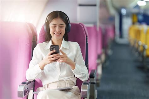 아름 다운 아시아 비즈니스 여자는 비행기에서 비행 중에 휴대 전화로 음악을 듣고있다 일 여행 비즈니스 개념 1인칭 시점에 대한