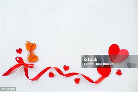 อมยิ้มสองอันริบบิ้นสีแดงและหัวใจบนพื้นหลังสีขาว หัวใจสีแดง แนวคิดแคนดี้เลิฟ วันวาเลนไทน ภาพสต็อก