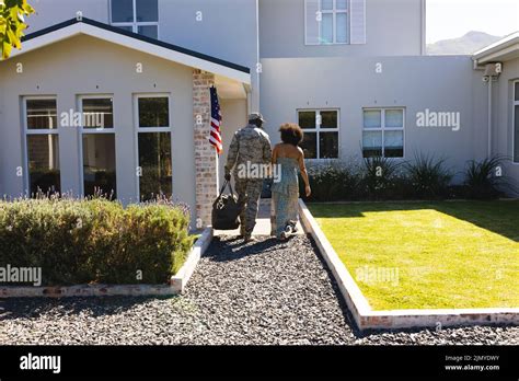 Rear View Of Multiracial Army Soldier In Camouflage Holding Wifes Hand