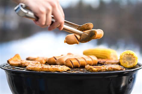 사람이 숯불 주전자 그릴 맛 있는 음식 가득 굽고 자연에서 야외 부엌에서 요리 남자 또는 여 자가 바베 큐 집게와 소시지를 손에