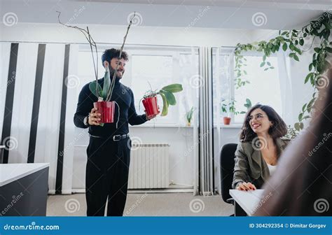 Cheerful Colleagues Sharing Office Plants In A Bright Modern Workspace