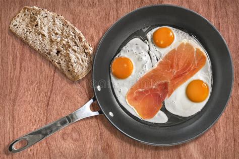 Яичницы и копченый Rasher ветчины в сковороде с куском хлеба на