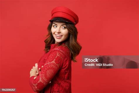 레이스 드레스에 웃는 젊은 여자의 측면도 모자 지주 손은 스튜디오에서 밝은 빨간색 벽 배경에 고립 된 옆을 보고 교차 사람들은 진심으로 감정 라이프 스타일 개념입니다 복사