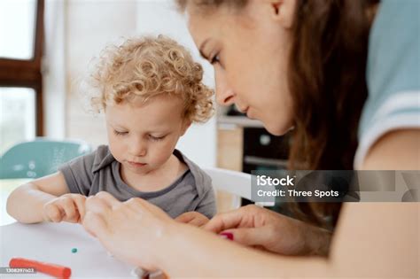 아름다운 어머니는 유치원에 살던 딸과 함께 식탁에 앉아 플라스틱에서 무언가를 만듭니다 엄마 이다 지출 그녀의 오후 자유 시간 와 그녀의 딸 2명에 대한 스톡 사진 및 기타