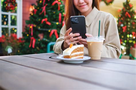 크리스마스 파티에서 커피 컵과 케이크를 테이블 위에 놓고 휴대폰을 들고 사용하는 여성의 클로즈업 이미지 35 39세에 대한 스톡 사진 및 기타 이미지 Istock