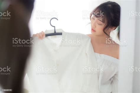 아름 다운 젊은 아시아 여자 방에 현대적이 고 보이는 반사 거울 피팅 드레스에 노력 옷으로 웃는 여자 행복 하 고 쾌활 한 옷
