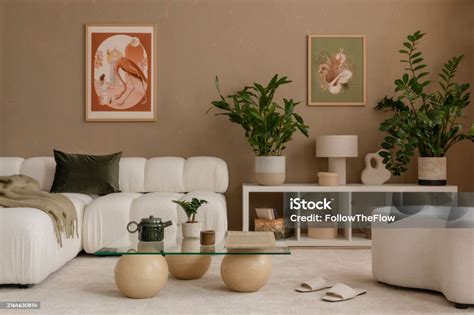 녹색 식물 모형 포스터 프레임 예술 Boucle 소파 세련된 커피 테이블 패턴 깔개 대리석 램프 및 개인 액세서리가있는 거실 인테리어의 따뜻하고 아늑한 가을 베이지 색 구성
