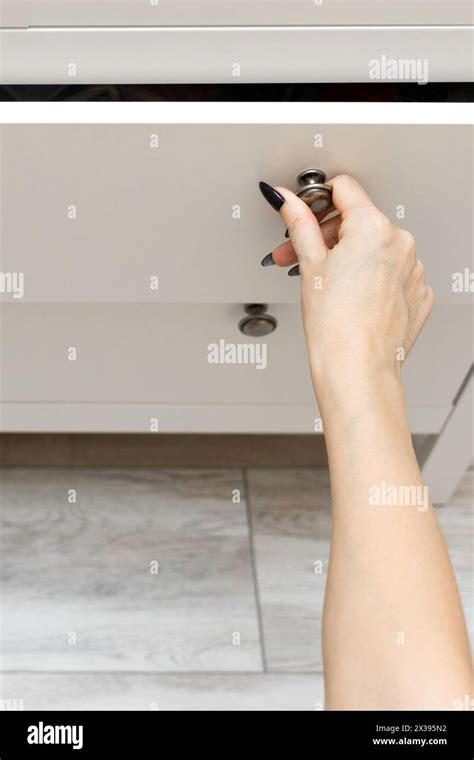 Woman Opens A Cabinet Drawer Using The Handle Woman Opens Cabinet Drawer Vertical Photo Stock