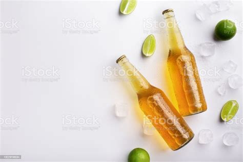 라벨이 없는 에일이 있는 투명한 유리 병 2개 흐르는 방울 얼음과 라임 조각이 놓여 있습니다 각얼음에 대한 스톡 사진 및 기타 이미지 Istock