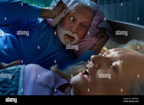 Elderly Woman Sleeping And Snoring While Husband Is Awake And Annoyed
