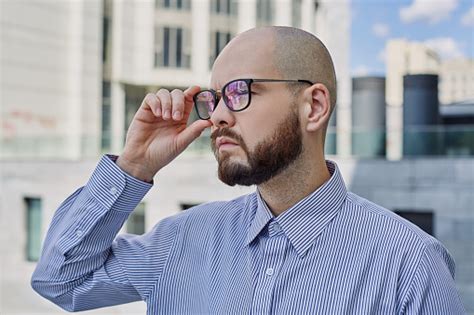 갈색 수염을 가진 한 사업가가 도시에 있는 건물과 함께 길거리에서 손으로 안경을 쓰고 서 있다 비즈니스 맨 직원 프로그래밍 거리에 대한 스톡 사진 및 기타 이미지 Istock