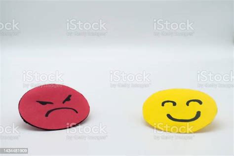 노란색은 배경에 또 다른 빨간색 화난 얼굴과 함께 종이 웃는 얼굴을 잘라냅니다 흰색 바탕에 부러움 이기심 행복 또는 복지의 개념