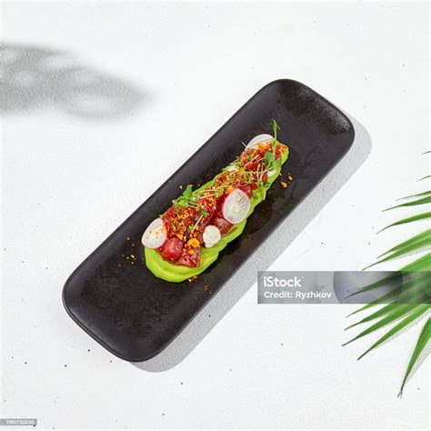 현대 음식 검은 접시에 슬라이스 아보카도에 참치 타르타르 아보카도 스타터와 참치와 무 아시아 스타일 현대 아시아 요리 흰색