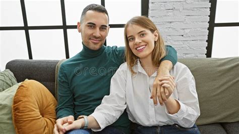 A Smiling Couple Cuddling On A Sofa In A Cozy Modern Living Room Portraying Love And