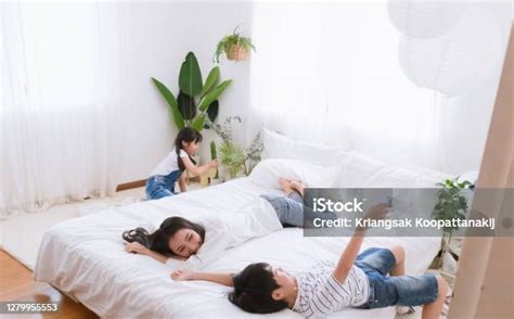 아늑한 집에서 사랑스러운 행복한 아시아 가족 웃는 어머니 아들과 딸은 침실에서 함께 휴식을 취하고 장난을 치는 것을 즐깁니다