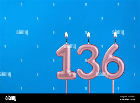 Number 136 Burning Anniversary Candle On Blue Foamy Background Stock