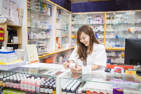 제품 세부 사항을 기록하는 웃는 얼굴을 가진 아시아 여성 약사 약국에 대한 스톡 사진 및 기타 이미지 약국 한 명의 여자만