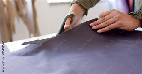 Hands Of Biracial Female Fashion Designer Cutting Cloth With Fabric
