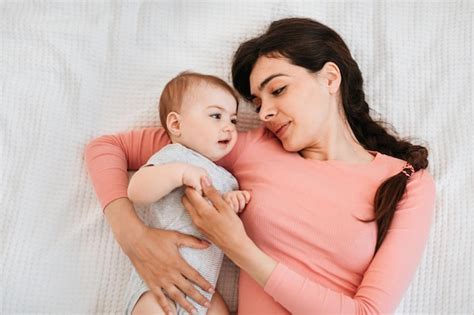 Conexión madre e hijo mujer joven acostada con su hijo pequeño en la cama tocando la mano de su