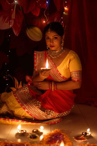 인도 전통 드레스를 입은 젊고 아름다운 인도 벵골어 여성이 화려한 보케 조명 앞에서 디왈리 디야 램프를 손에 들고 있다 30 34세에 대한 스톡 사진 및 기타 이미지