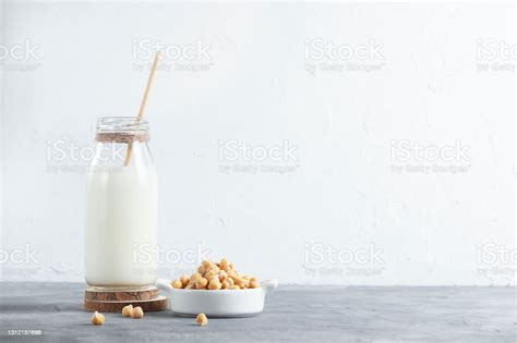 흰색 배경에 친환경 종이 빨대가 있는 유리 병에 담긴 생 병아리콩으로 만든 채식주의자와 채식주의자를 위한 대체 우유 0명에 대한