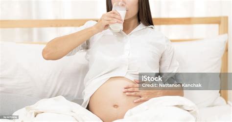 닫기 최대의 A 임신 여자 신선한 우유 또는 물 유리를 손으로 그녀의 배꼽을만 지 큰 배와 함께 행복 한 여자입니다 임신 및