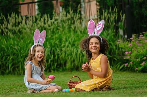 A Two Girls During Easter Egg Hunt And Putting Easter Eggs In Baskets Stock Photo Image Of