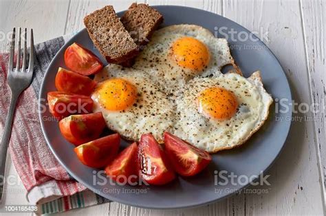 3 튀긴된 계란 소금 하 고 토마토와 흰색 나무 테이블에 큰 접시에 호 밀 빵 매운 가정식 식사입니다 0명에 대한 스톡 사진 및