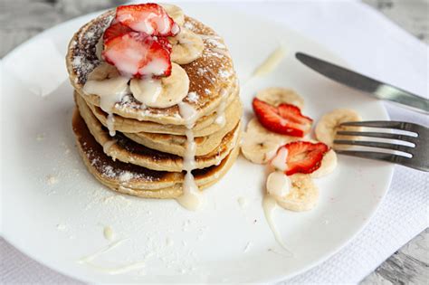 밝은 배경에 흰색 접시에 신선한 딸기와 팬케이크의 스택 아침 식사 옆에 유리 꽃병에 흰 꽃이 서 있습니다 건강한 생활방식에 대한 스톡 사진 및 기타 이미지 Istock