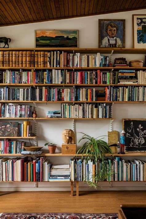 A Bookshelf Filled With Lots Of Books Next To A Painting On The Wall