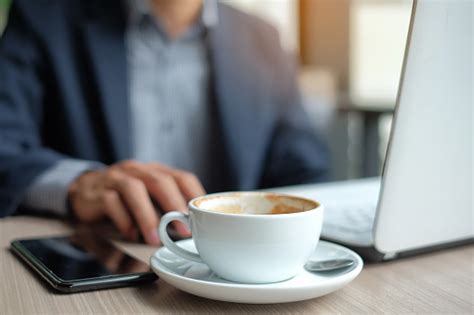 사무실에서 일하는 동안 노트북과 스마트 폰을 사용하여 사업가와 뜨거운 커피 한 잔 비즈니스 인터넷 기술 및 통신 개념 개념에