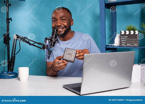 Smiling Vlogger Recording Review For Website Sitting At Desk With