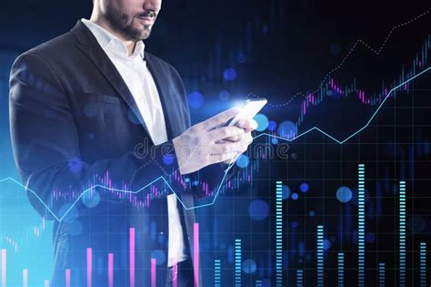 Man Using Smartphone With Overlay Of Stock Market Graphs Digital Style On A Dark Blue