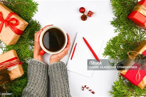크리스마스 배경에 커피 머그잔을 들고 손 위에서 볼 수 있습니다 커피 컵을 들고 있는 여성의 손 나무 테이블 위에 크리스마스 선물 상자와 눈 전나무 나무 복사 공간이 있는