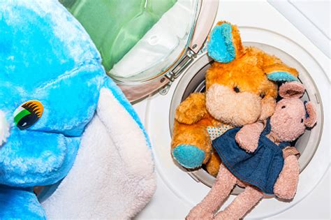 봉제 인형 토끼와 테디 베어는 세탁기에 앉아 씻기를 기다리고 있습니다 파란색 코끼리가 차 근처에 앉아 있습니다 그는 이미