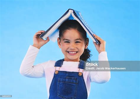 학교 머리 그리고 지식을 위한 책이나 학습을 위한 책이 있는 아이의 초상화는 스튜디오 파란색 배경에 고립되어 있다 영리하고