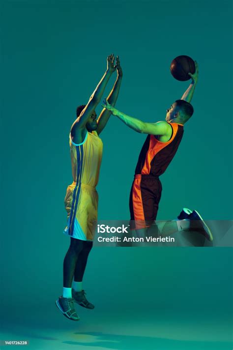 두 젊은이 프로 농구 선수가 점프를하고 네온의 푸른 배경에 고립 된 바구니에 공을 던지는 초상화 18 19세에 대한 스톡 사진 및 기타 이미지 Istock