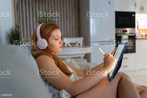 여성 프리랜서 그래픽 디자이너가 집에서 디지털 태블릿으로 작업하면서 음악을 듣습니다 20 24세에 대한 스톡 사진 및 기타