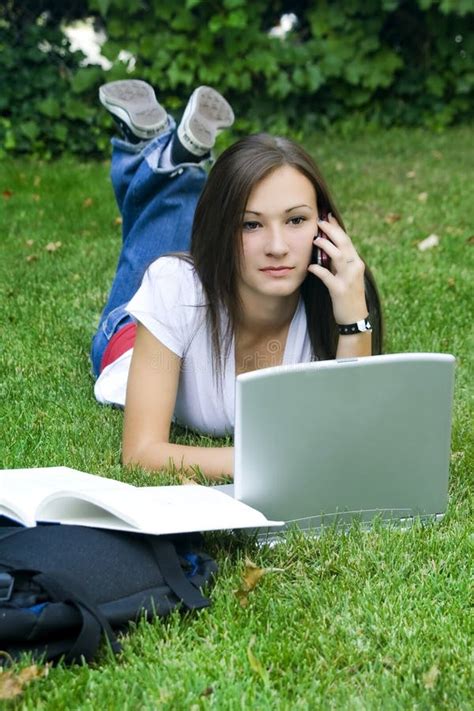 Het Meisje Van De Tiener Op De Telefoon Die Op Het Gras Bepaalt Stock