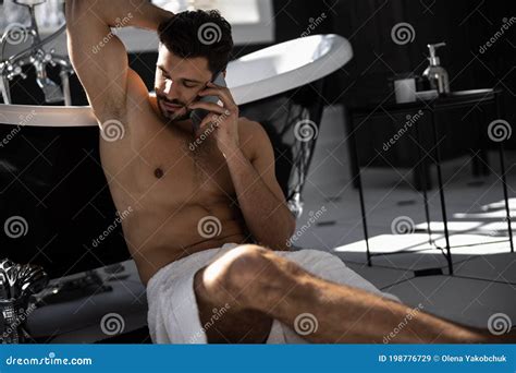 Handsome Man Wrapped In Towel Talking On Mobile Phone And Sitting On