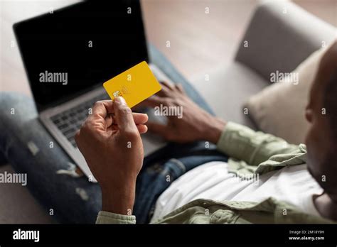 Adult Black Male Typing On Computer Keyboard With Empty Screen Using Credit Card For Online