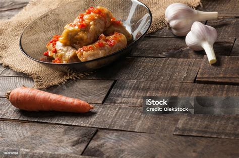 삶은 양배추 롤의 한 부분과 쌀과 고기로 채워진 토마토 소스가 마늘 근처의 검은 유리 판에 당근은 가라앉고 소박한 나무 테이블에
