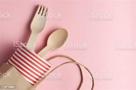 환경 친화적이고 일회용 주방 용품 템플릿 나무 숟가락 포크 종이 컵 분홍색 산호 배경의 종이 패키지로 구성 평평한 평신도 복사